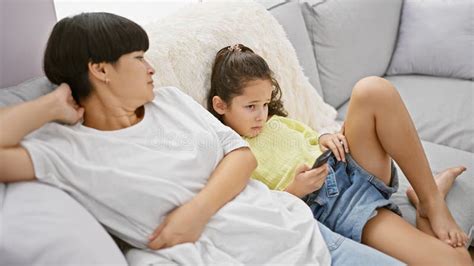 Tired Mother And Bored Babe Sitting Comfortably On Their Living Room Sofa Expressionlessly