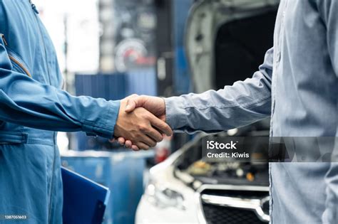 아시아 자동차 정비사 수리공이 차고에서 고객과 악수를 하고 있습니다 정비사 워크숍에서 일하는 차량 서비스 관리자는 고객을 위한 점검 및 유지 보수 자동차 엔진 을 확인한 후