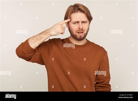 Idiotic Plan Portrait Of Bearded Man Showing Stupid Gesture Pointing Finger To Temple And