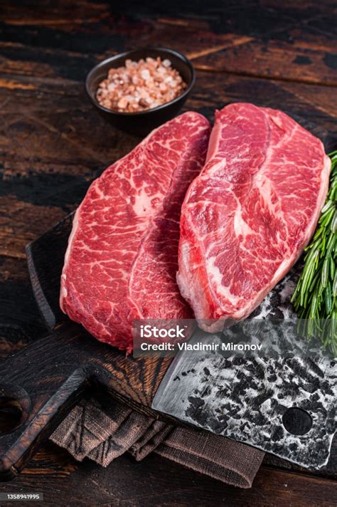 조리되지 않은 생 숄더 탑 블레이드 또는 고기 칼이있는 나무 정육점에 있는 평평한 철 쇠고기 고기 스테이크 어두운 나무 배경 맨 위 보기 0명에 대한 스톡 사진 및 기타