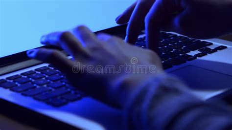 Hands Typing On A Laptop Keyboard In A Dimly Lit Room At Night Stock