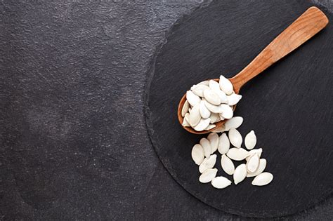 호박 씨앗과 어두운 테이블에 나무 숟가락 검은 색 슬레이트 보드와 나무 그릇 공간을 복사합니다 0명에 대한 스톡 사진 및 기타