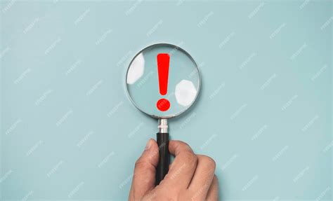 Premium Photo Hand Holding Magnifier Glass With Red Triangle Caution Warning Sign For