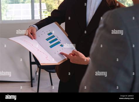 two unrecognizable men in suits analyzing performance charts of a