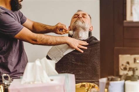 Premium Photo Barber Trimming And Cutting Bearded Man With Shaving Machine In Barbershop