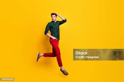 매혹적인 우아한 남자의 전체 길이 프로필 측면 사진 느낌 꿈꾸는 표정 점프 실행 착용 캐주얼 스타일 의상 운동화 노란색 색상