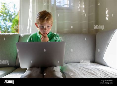 Young Handsome Boy Thinking While Using Laptop On The Couch At Home