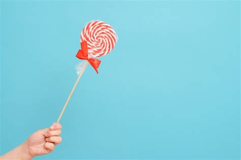 Premium Photo Candy Cane In Hand Isolated On Blue