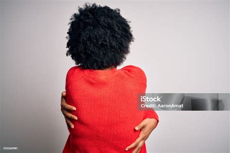 젊은 아름 다운 아프리카 계 미국인 Afro 여자 곱슬 머리 를 입고 빨간 캐주얼 스웨터 포옹 자신 포옹 자신 에서 뒤로 자기 사랑과 자기 관리 곱슬 머리에 대한 스톡 사진