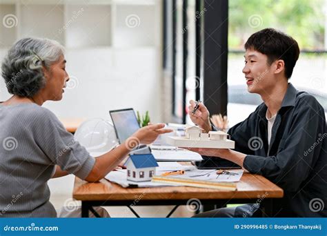 A Retired Asian Female Client Discussing Her Home Building Design With An Architect In The
