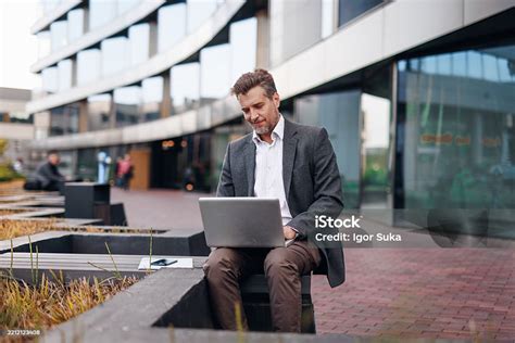현대식 사무실 건물 밖에 앉아 노트북을 들고 일하는 사업가 40 49세에 대한 스톡 사진 및 기타 이미지 40 49세 거리 건물 외관 Istock