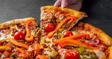 여자 손모짜렐라 치즈 볼로네즈 소스 다진 고기 후추 토마토 베이컨 야채와 피자의 조각을 합니다 다크 그레이 블랙 슬레이트 배경에