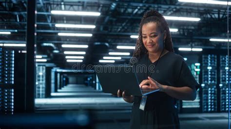 Black Female Chief Technology Office Using Laptop Computer Standing In Big Office Data Center