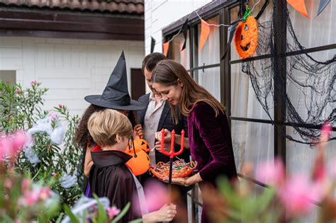 집에서 함께 할로윈 파티를 축하하는 다인종 아이들 할로윈 의상을 입은 귀여운 어린 아이들이 트릭 오어 트릿 호박 바구니를 들고 집에서 축제 기간 동안 사탕을 받고 있습니다
