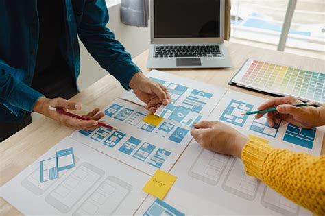 Ux 개발자와 Ui 디자이너가 현대 사무실에서 고객 요약 및 색상 코드와 함께 테이블에 모바일 앱 인터페이스 와이어프레임 디자인에 대해 브레인스토밍합니다 크리에이티브 디지털