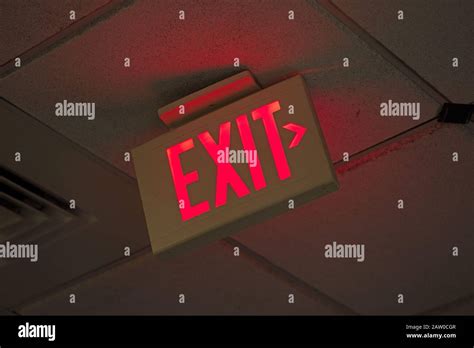 Red Lighted Exit Sign On Drop Ceiling With Arrow Stock Photo Alamy