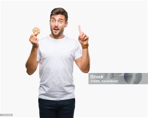 젊은 잘생긴 사람을 먹는 초콜릿 칩 쿠키 격리 된 배경에 아이디어 또는 질문 넘버 원 행복 한 얼굴로 손가락을 가리키는 놀 가리키기에 대한 스톡 사진 및 기타 이미지