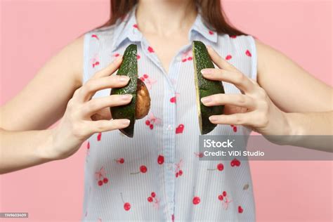 자른 이미지 여름 옷에 젊은 여자 핑크 파스텔 벽 배경에 고립 된 신선한 잘 익은 아보카도 과일의 Halfs 손에 개최 합니다 사람들은 생생한 라이프 스타일 휴식 휴가
