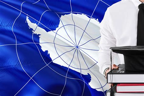 성공적인 학생 교육 개념입니다 남극 국기 배경 위에 책과 졸업 모자를 들고 교사 교육 관련 직업에 대한 스톡 사진 및 기타 이미지 교사 교육 관련 직업 교육 기