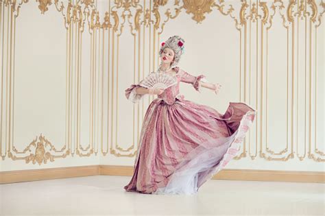핑크 바로크 양식의 가운을 입은 우아한 여성이 빈티지 인테리어에서 우아하게 춤을 추며 과거와 현재의 본질을 포착합니다 16 17 살에 대한 스톡 사진 및 기타 이미지