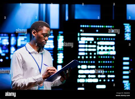 Licensed It Admin Walking In Server Hub Performing Data Backups And Providing Centralized