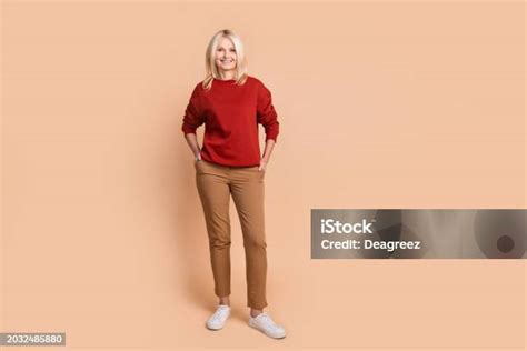 좋은 분위기 예쁜 여자 입고 빨간 스웨터 웃고있는 빈 공간 외딴 베이지 색 배경의 전체 길이 사진 50 54세에 대한 스톡 사진