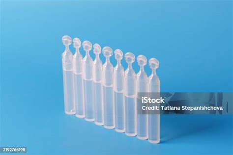 부드러운 파란색 배경에 투명한 약물로 채워진 투명한 플라스틱 앰플의 수직 배열은 제약 제품 및 건강 관리 개념을 강조합니다 0