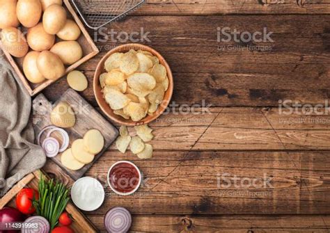 신선한 유기 집에서 만든 감자 감자칩 나무 테이블 배경에 사 워 크림과 붉은 양파와 향신료와 나무 그릇에 평면도 케첩을 사용한 신선한 노란 감자 0명에 대한 스톡 사진 및