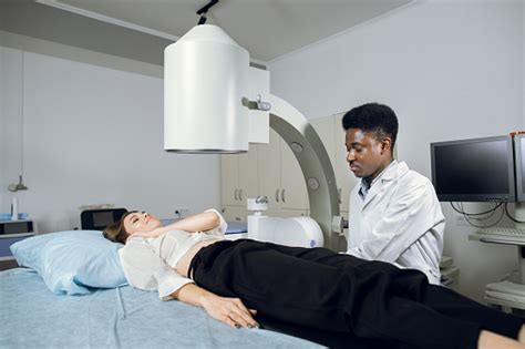 젊은 고숙련 집중 흑인 남자 의사 흰색 코트에 돌을 깰 현대 초음파 리소 트립터와 그의 거짓말 여성 환자에 대한 Lithotripsy 절차를 제공 2명에 대한 스톡 사진 및