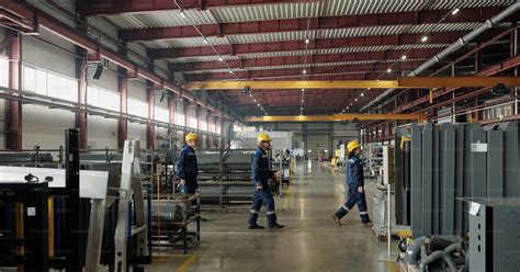 안전모와 파란색 작업복을 입은 공장 직원들이 업계의 압축기 장치 사이에 줄을 서서 걷고 있다 사진 Unsplash의 공장 이미지