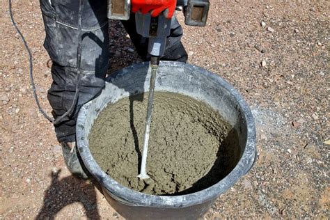 기초 및 양식 작업 건설 현장에서 양동이에 콘크리트를 혼합하는 남성 노동자 손 믹서와 전기 드릴시멘트 또는 모르타르를 혼합