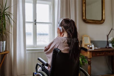 Unhappy Teenage Girl Sitting On A Wheelchair And Looking Out Of The