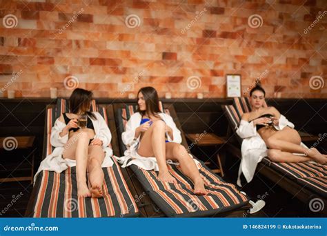 A Group Of Young Girls Relaxing On A Wooden Deck In The Sauna Having