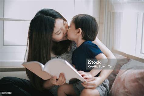 아시아 의 중국 임신 여자 앉아 낮 시간 침대 휴식 와 함께 A 한 잔 의 차 즐기고 독서 책 과 그녀의 아들 안기에 대한 스톡 사진 및 기타 이미지 Istock