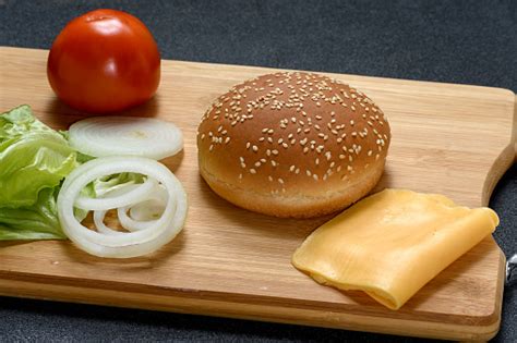 간식 준비 재료 참깨 양파 토마토 치즈 양상추를 곁들인 빵을 어두운 배경의 도마에 얹습니다 0명에 대한 스톡 사진 및 기타