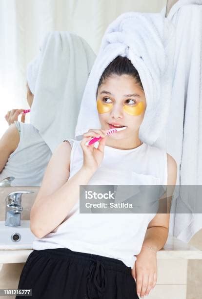 황금 보습 패치 소녀는 화장실에서 치아를 닦고 멀리 보인다 아침에 테리 수건에 행복 한 소녀입니다 힐티 스킨케어 및 웰빙 컨셉