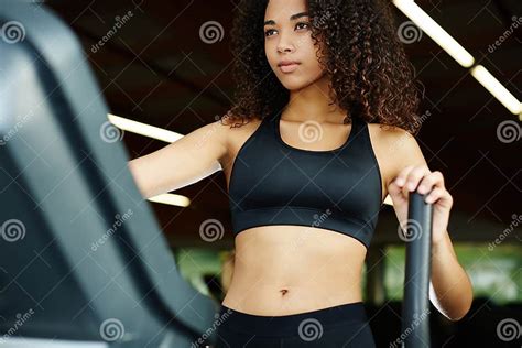 Woman Dressed In Sports Bra Working Out On Stepping Machine In Gym