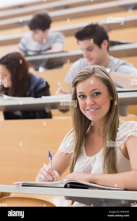 Woman Sitting While Smiling At The Lecture Hall And Taking Notes Stock Photo Alamy