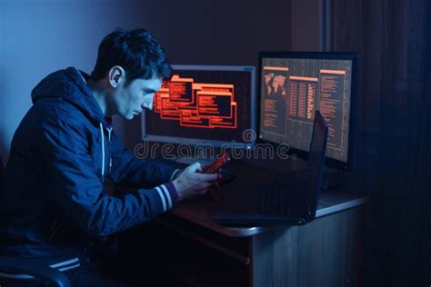 Male Hacker Holding The Phone In His Hands Trying To Hack The Mobile