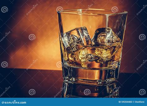 Glass Of Whiskey On Black Table With Reflection And Gold Background