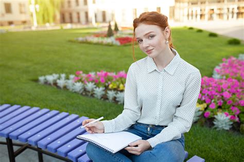 노트북에 메모 하 고 벤치에 앉아 주 근 깨와 아름 다운 젊은 빨간 머리 소녀 학생의 초상화입니다 원격 교육입니다 숙제 개념에 대한 스톡 사진 및 기타 이미지 Istock
