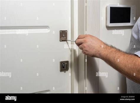 Master Repairing A Door Lock In A Room A Man Fixing A Lock With A Screwdriver Close Up Of A