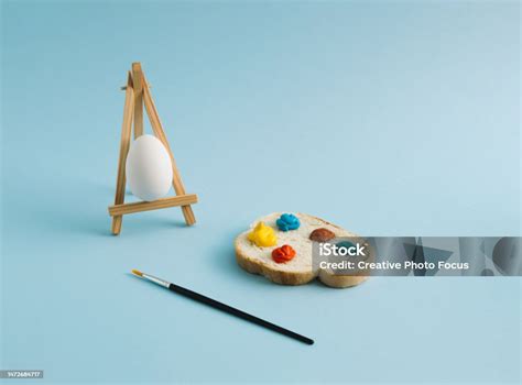 이젤에 흰 계란으로 만든 추상 부활절 구성과 다채로운 팔레트가 있는 빵 조각 파스텔 블루 배경입니다 공간을 복사합니다 0명에 대한 스톡 사진 및 기타 이미지 Istock