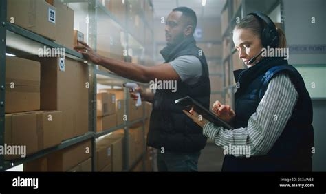 African American Employee Scans Parcels With E Commerce Goods With Scanner Female Warehouse