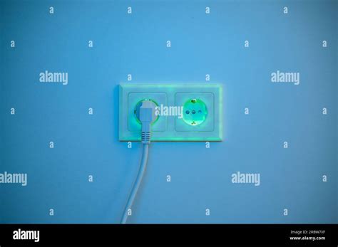 Green Illuminated Socket With Plug Inserted To Symbolise Power Consumption And Electrical Energy