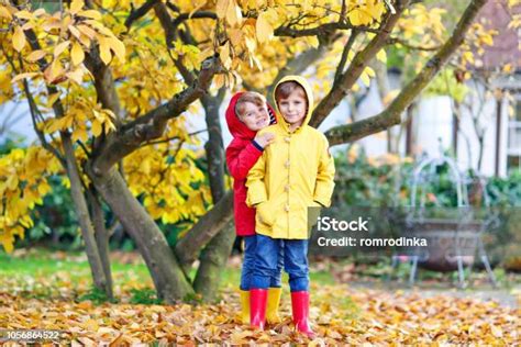 두 명의 작은 최고의 친구와 화려한 옷에 아이 소년이을 공원 행복 한 형제 어린이 빨간색과 노란색 레인 코트와 고무 장화에 재미
