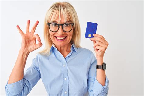 고립된 흰색 배경 위에 신용 카드를 들고 안경을 쓰고 있는 중년 사업가가 손가락으로 확인 사인을하고 훌륭한 상징 개념에 대한 스톡 사진 및 기타 이미지 Istock