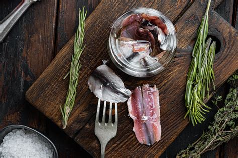 오래된 어두운 나무 테이블 배경에 나무 도마에 통조림 멸초비 허브와 재료로 최고 보기 플랫 레이 0명에 대한 스톡 사진 및 기타