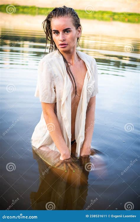 A Beautiful Brunette Model In A Wet Shirt Posing On The Sand In Front