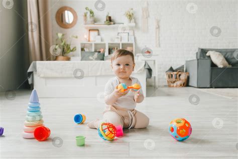 малыш 6-9 месяцев играет с разноцветной радужной игрушечной пирамидкой ...